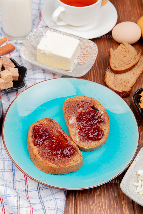 side view of breakfast set with rye bread slices smeared with jam in ...