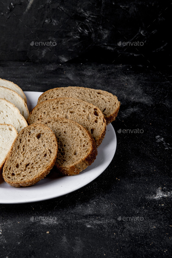 side view of plate full of sliced black and white breads on left side ...