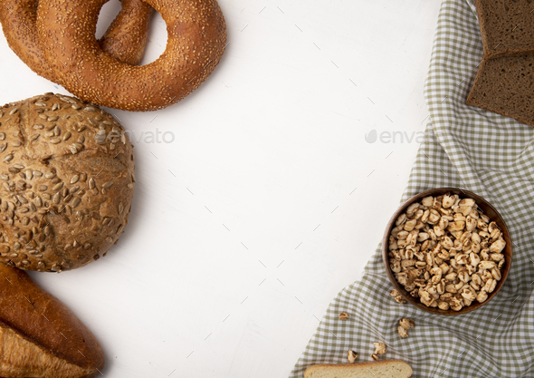 side view of breads as cob, bagel, baguette, rye with bowl full of ...
