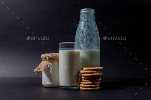 side view of milk products as bottle and glass of milk, cream in jar ...