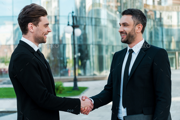 Men handshaking. Two confident young businessmen shaking hands and ...