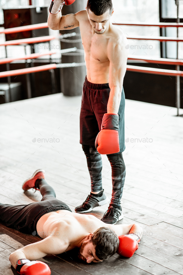 Boxer winner with beaten man on the boxing ring Stock Photo by RossHelen