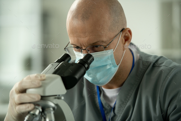 Concentrated lab worker using microscope Stock Photo by Pressmaster