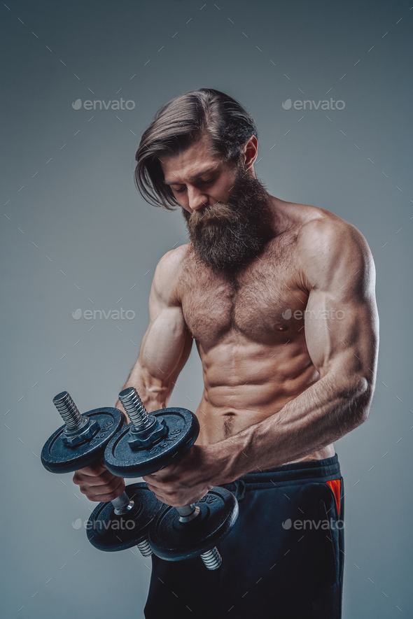 Athletic man with muscular build posing with dumbells in studio Stock ...