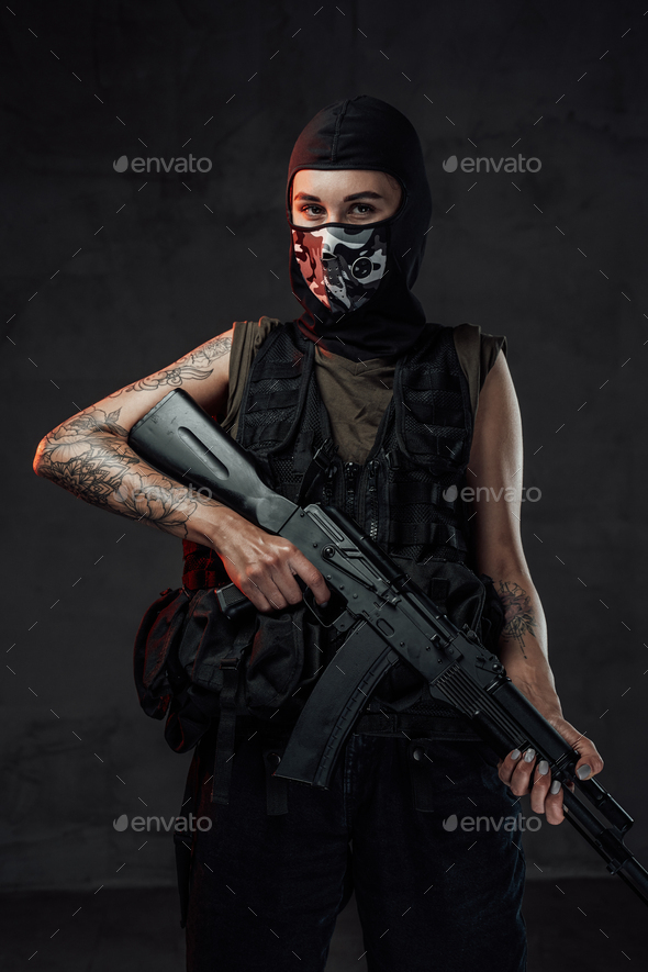 Female soldier poses in dark background holding assault rifle Stock ...
