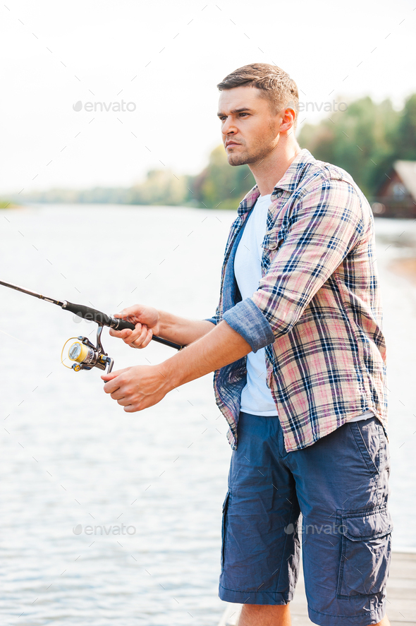 Good day for fishing. Confident young man fishing while standing on ...