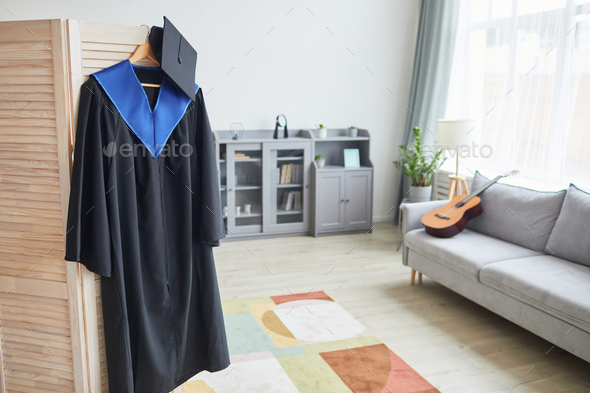 Graduation gown on hanger at home Stock Photo by seventyfourimages