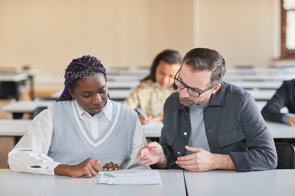 Professor helping students in class Stock Photo by seventyfourimages