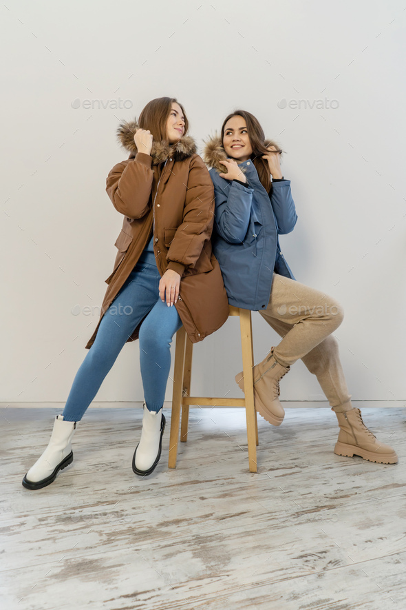 Two young women wearing jackets on gray. Stock Photo by maksimovata