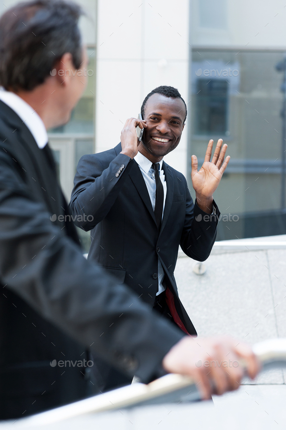Hello! Cheerful young African man in formalwear moving up by stairs and ...