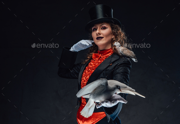 Female conjurer with top hat and white birds in dark background Stock ...