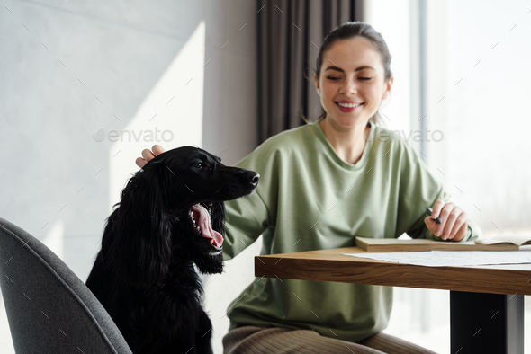 Happy brunette young woman petting her dog Stock Photo by vadymvdrobot