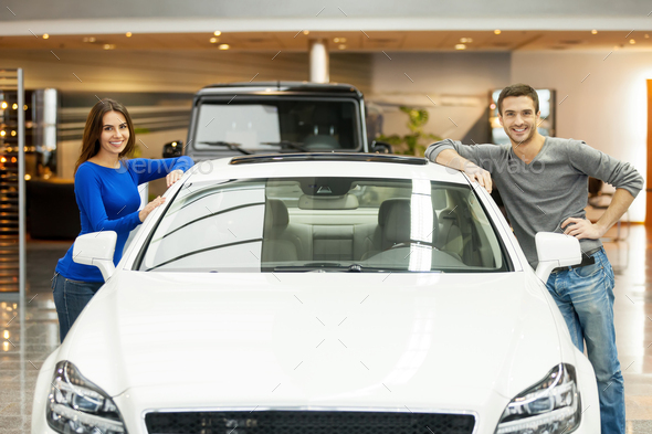 Happy with their new car. Happy young couple standing at both sides of ...