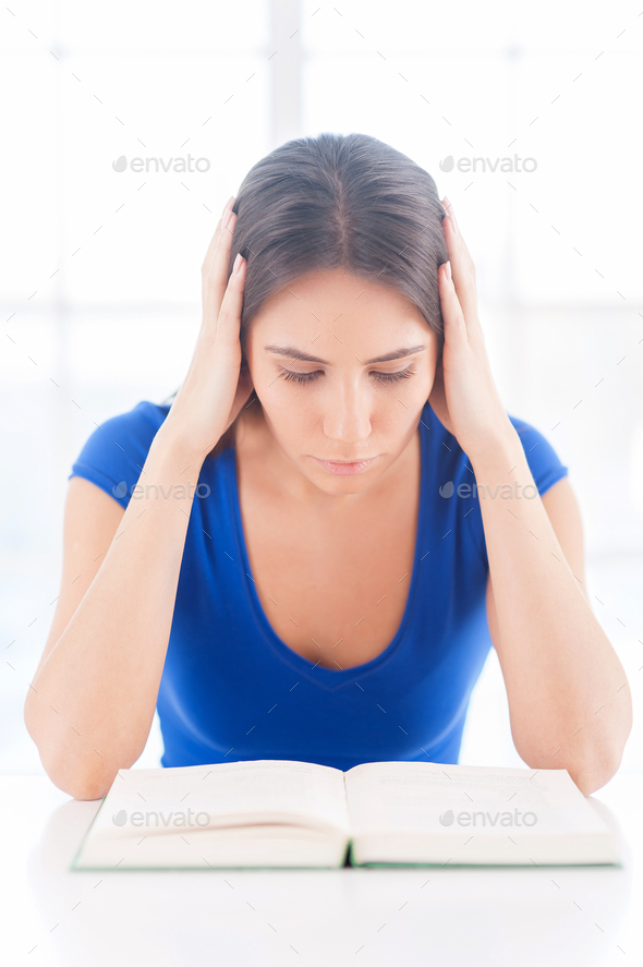 Reading a boring book. Frustrated young woman reading a book and ...