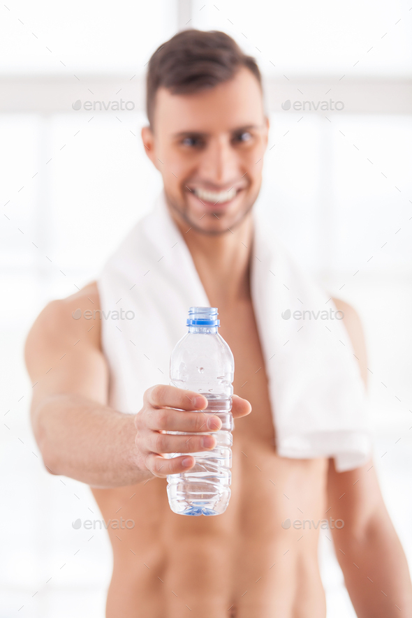 Get refreshed! Cheerful young muscular man holding a bottle with water ...