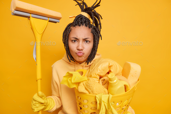 Dissatisfied sad woman pouts lips looks angrily at camera does house ...