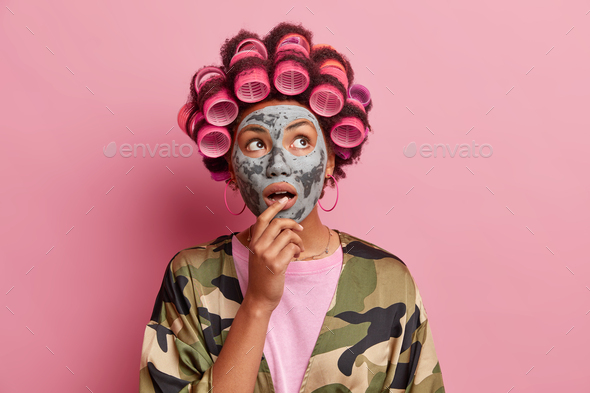 Portrait Of Surprised Housewife Applies Clay Mask On Face Looks