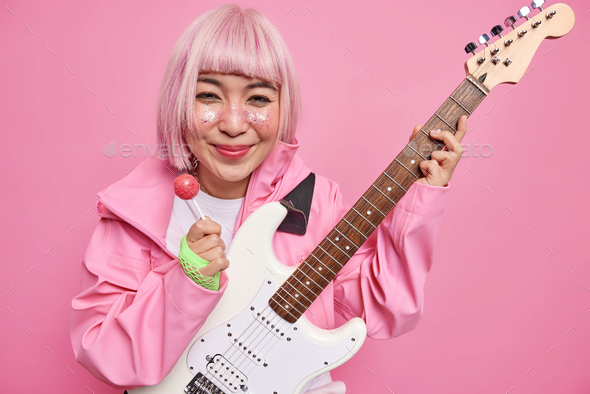 Lets rock. Famous stylish pink haired female singer poses with musical ...