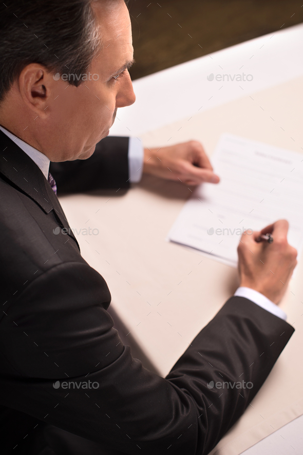 Signing a contract. Top view of mature man in formalwear signing a ...