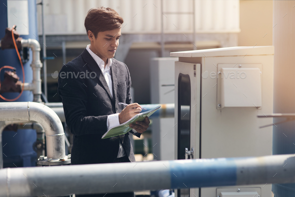 Trainee engineer making notes while checking the pipeline Stock Photo ...