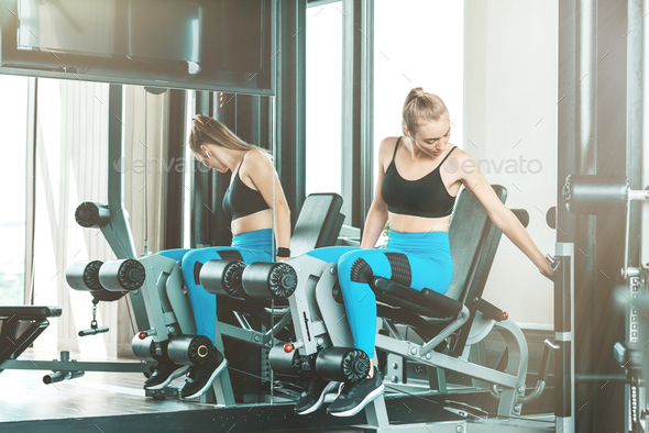 Shaping the legs. Fitness girl exercising on leg extension machine ...