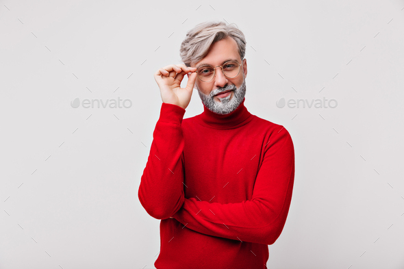 Joyful old man looking through the glasses with interest. Studio photo ...