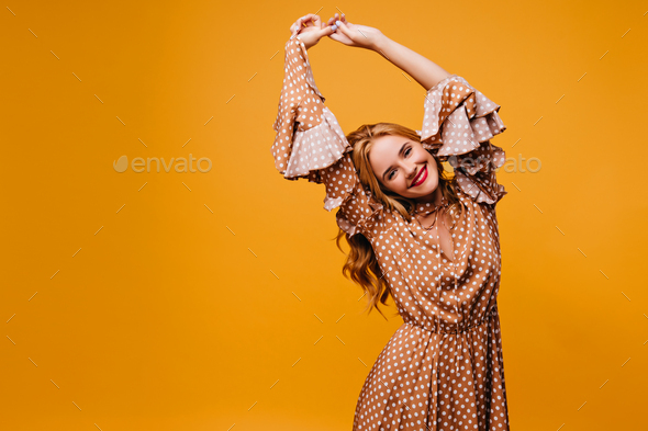 Jocund female model in elegant vintage attire smiling to camera. Indoor ...