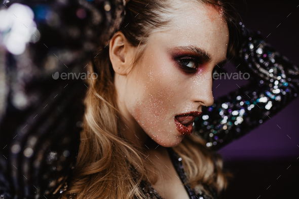 Refined woman in sparkle attire posing on dark background. Close-up ...