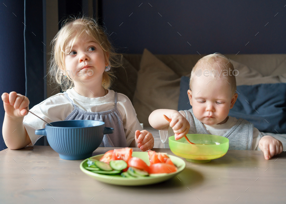 Two kids eating soup and vegetables for lunch at home Stock Photo by ...