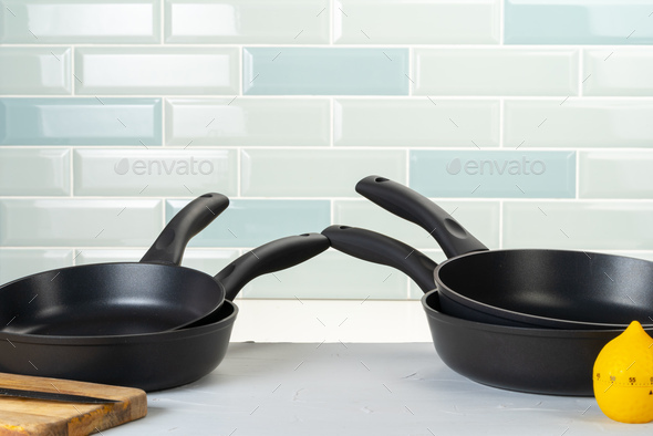 Clean and dry cooking pans on a kitchen counter Stock Photo by FabrikaPhoto