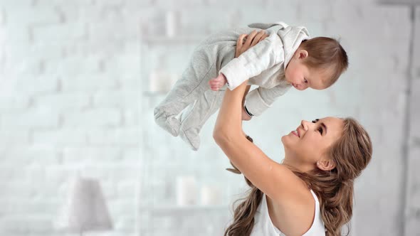 Attractive Mother Admiring Little Baby Rising Up Over Head Having Fun ...