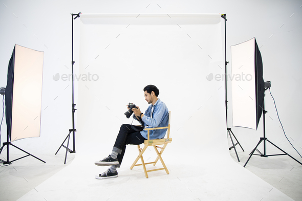 Young photographer man sitting wood chair and checking file on center ...
