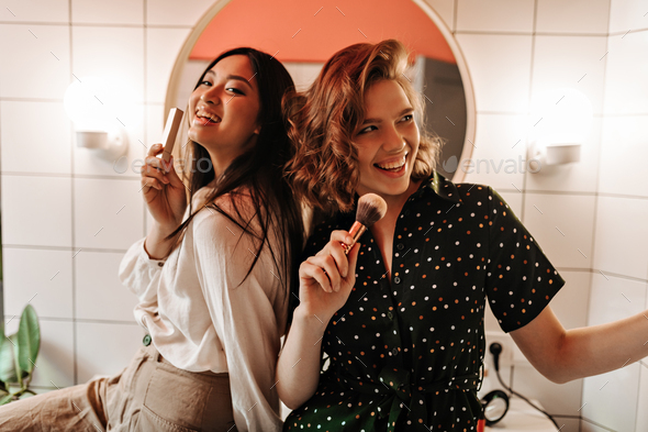 Carefree ladies having fun while doing makeup together. Two ...