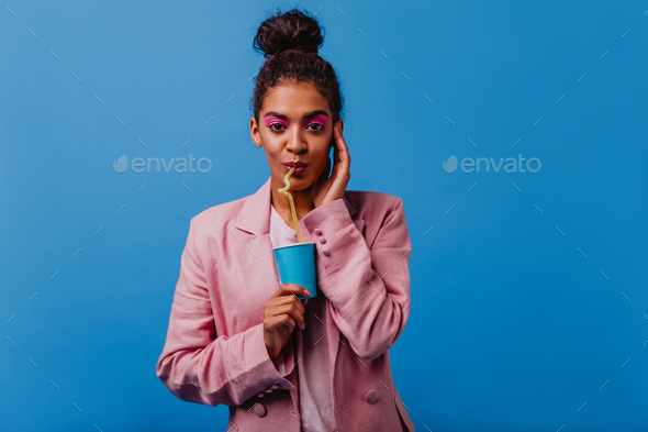 Well-dressed young woman drinking soda during photoshoot. Refined ...