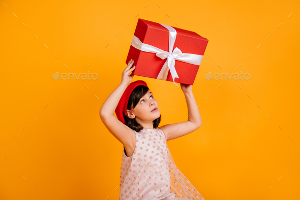 Interested brunette kid guessing what in present. Studio shot of little ...