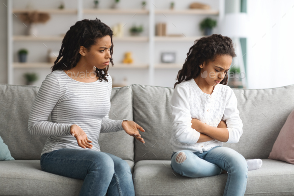 Angry mother scolding daughter, sitting on couch at home Stock Photo by Prostock-studio