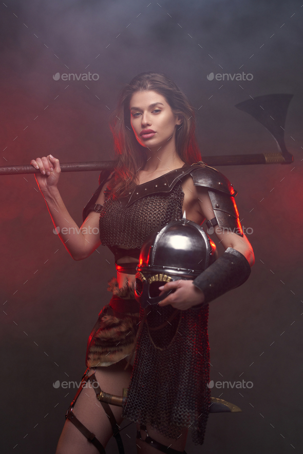 Wild northern valkyrie with axe and helmet in smoke Stock Photo by fxquadro
