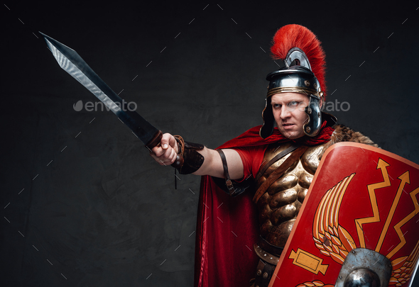 Angry roman soldier points sword against dark background Stock Photo by ...