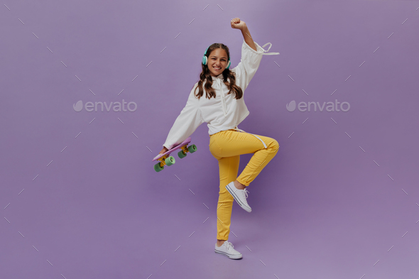 Active teenager moves on purple background and holds longboard. Young ...