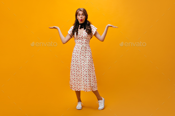 Surprised lady shrugging on orange background. Trendy young woman with ...