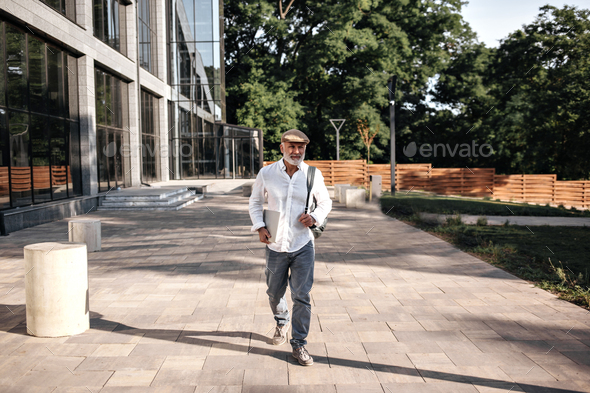 Man in baggy jeans and cap walks outside. Stylish adult guy in white ...