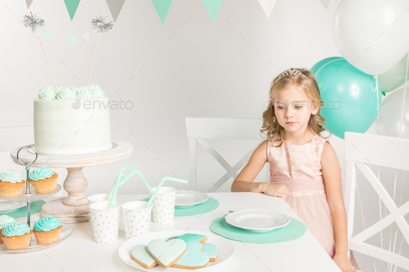 Adorable little girl sitting at birthday table with delicious sweets ...