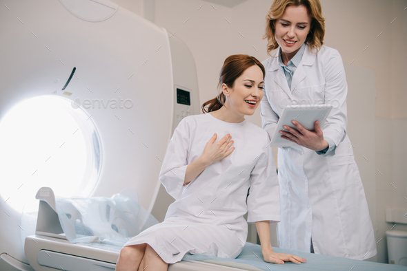 smiling radiologist showing x-ray diagnosis to happy patient sitting on ...