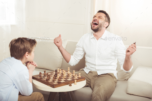 man celebrating win in chess game with upset son near by Stock Photo by ...