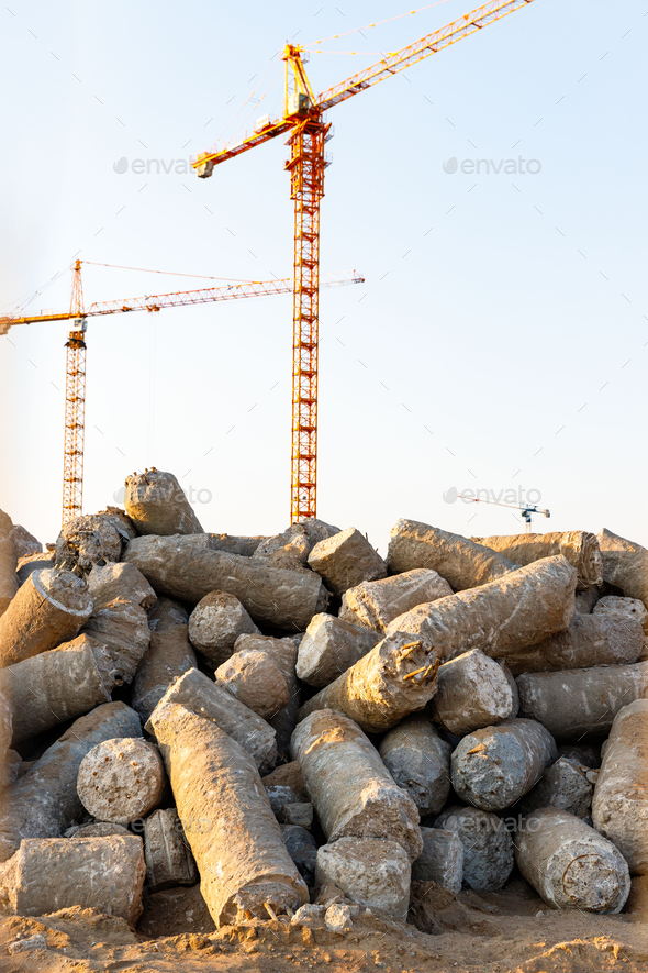 Big pile of cut concrete piles at construction site, tower cranes on ...