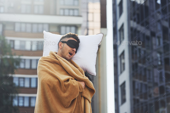 Business building at background. Young man in pajama is outdoors on the ...