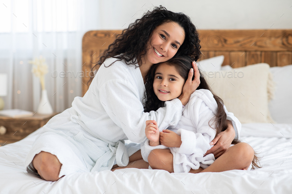 Cheerful young mother hugging her little daughter Stock Photo by Prostock-studio