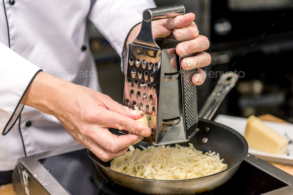 cropped image of chef grating cheese on grater Stock Photo by ...