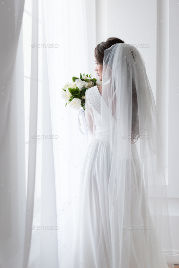 back view of brunette bride in wedding dress with traditional veil and ...