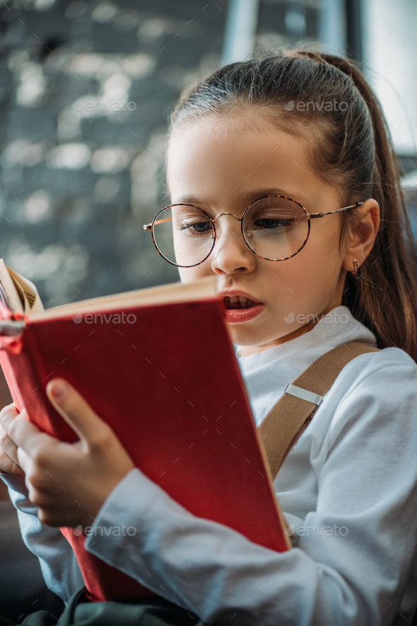 close-up portrait of concentrated little child reading book Stock Photo ...